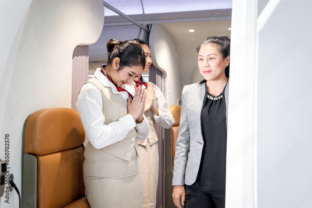 Beautiful Asian female air hostess standing and greeting at airplane ...