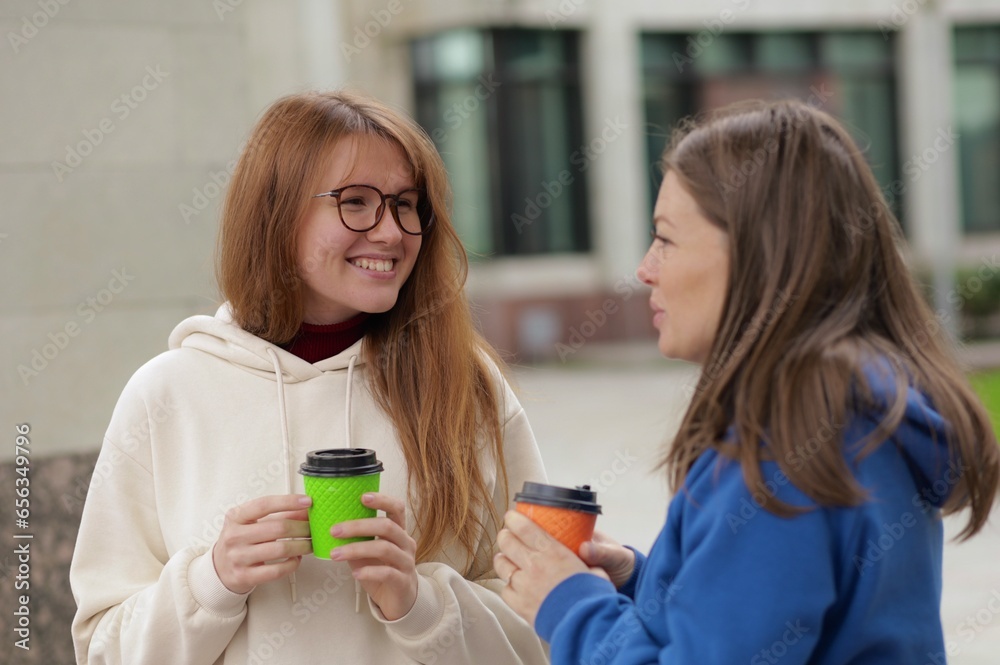 Two friends girls, young women students chat, talk with each other and ...