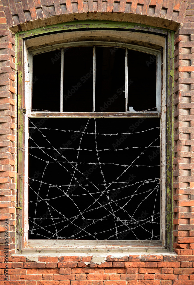 facade of red brick building with window frame from barbed wires. rusty ...