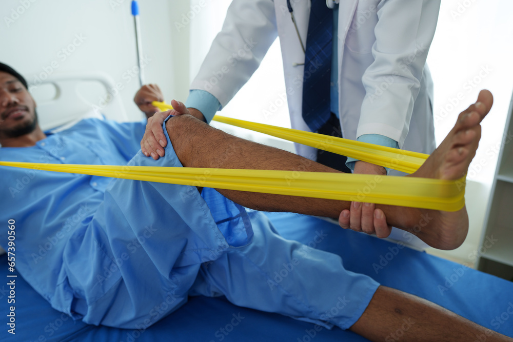 Physical therapist gives resistance band therapy to the legs and knees ...