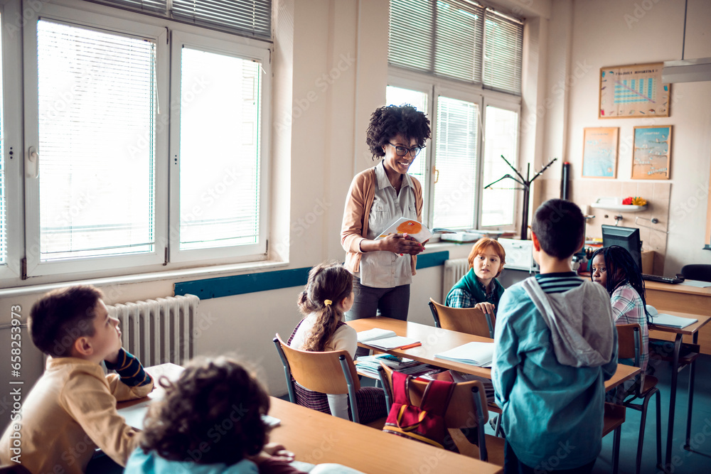Young African American female teacher questioning a young pupil in a ...