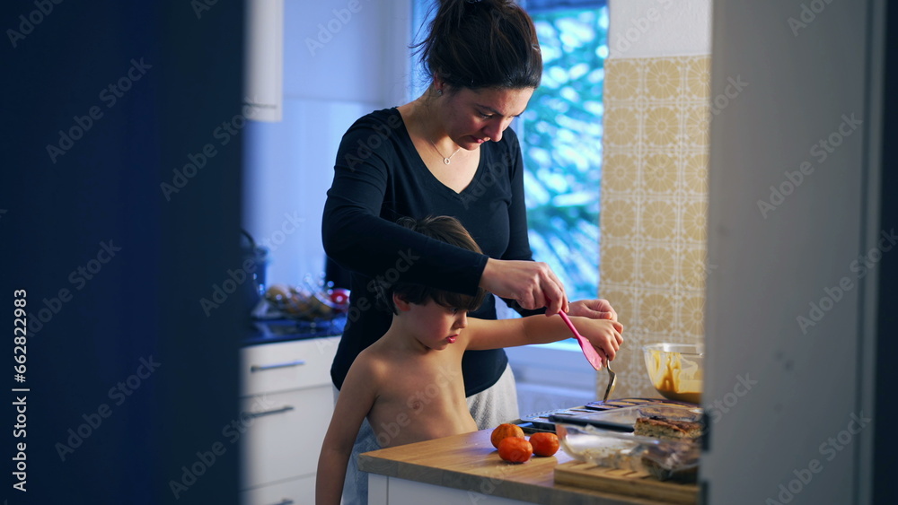 Candid mother and child cooking at home, preparing pastry food together ...