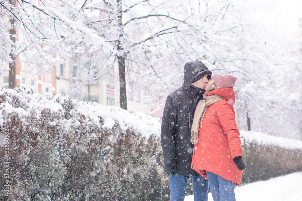Happy amorous couple hugging each other and kissing at snow day in ...