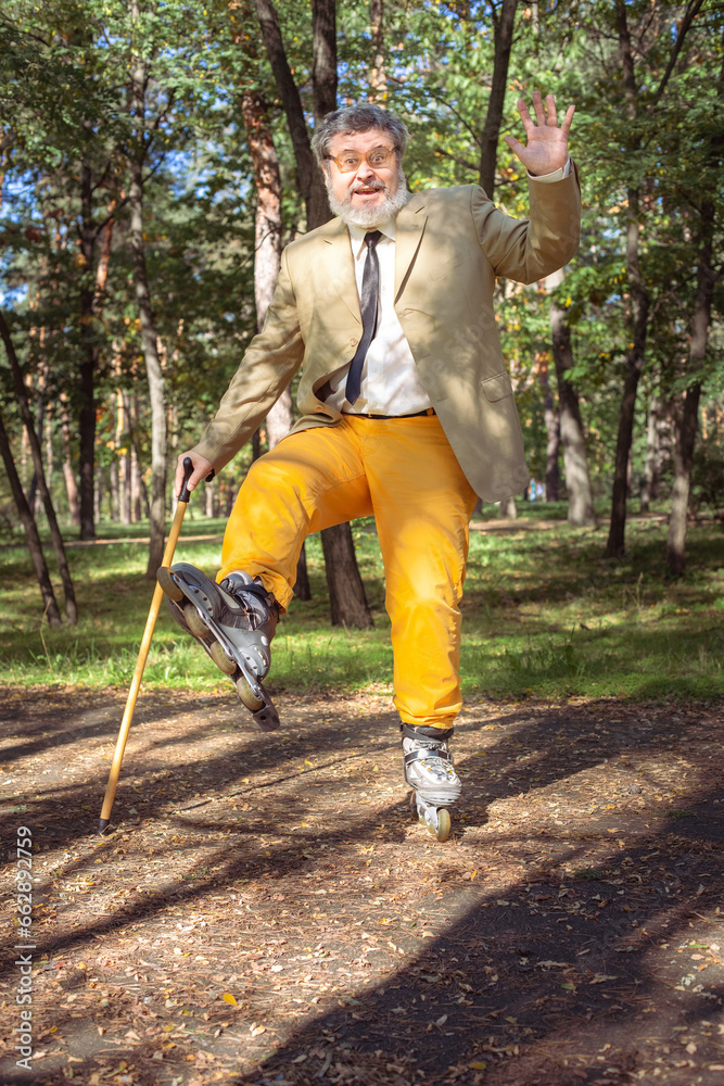 Funny old man is roller skating in the park. An active grandfather with ...