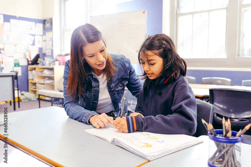 Aboriginal female school teacher sitting with her student in the ...