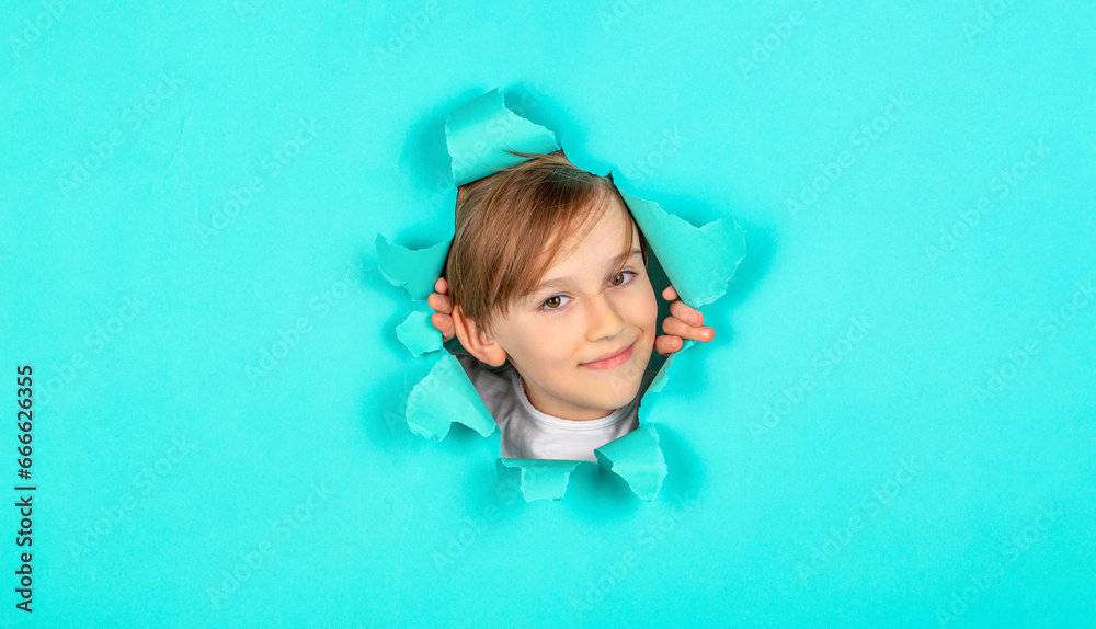 Positive child with toothy pleasant smile on face, keeps through torn ...
