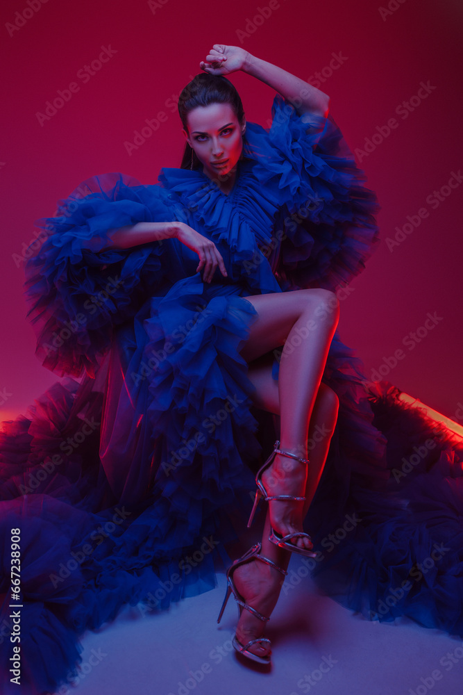 Beautiful model in a lavish blue carnival gown poses in a warmly lit ...