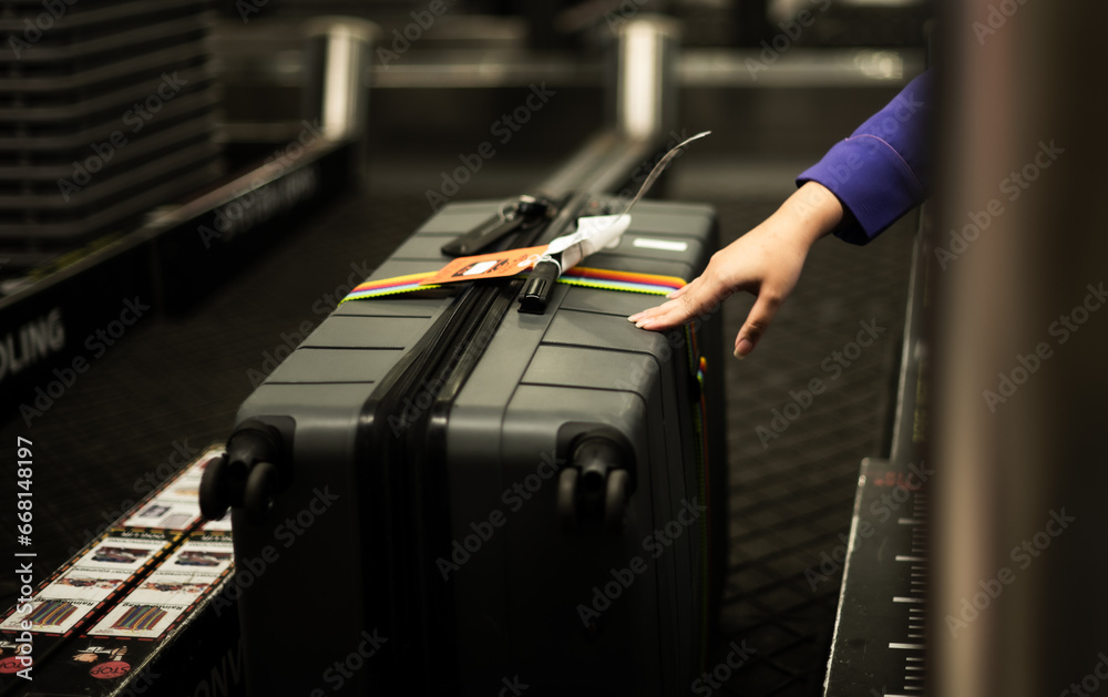 An airline employee is loading suitcases on a baggage delivery conveyor ...