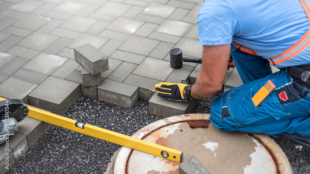 Laying interlocking paving. A worker's hand is placing interlocking ...