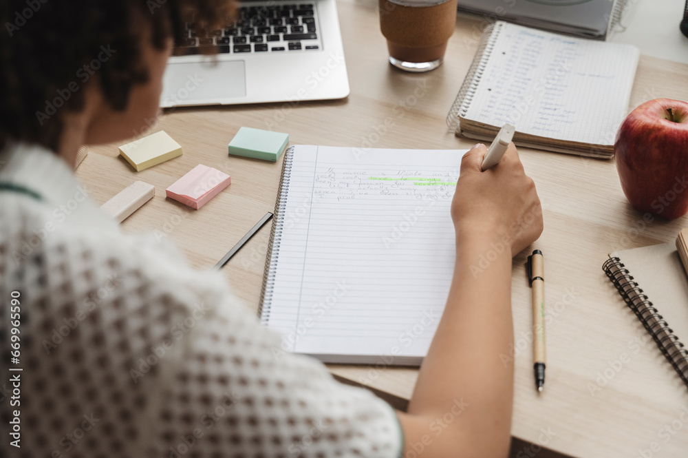 Teenage girl making notes on notepad at desk Stock Photo | Adobe Stock
