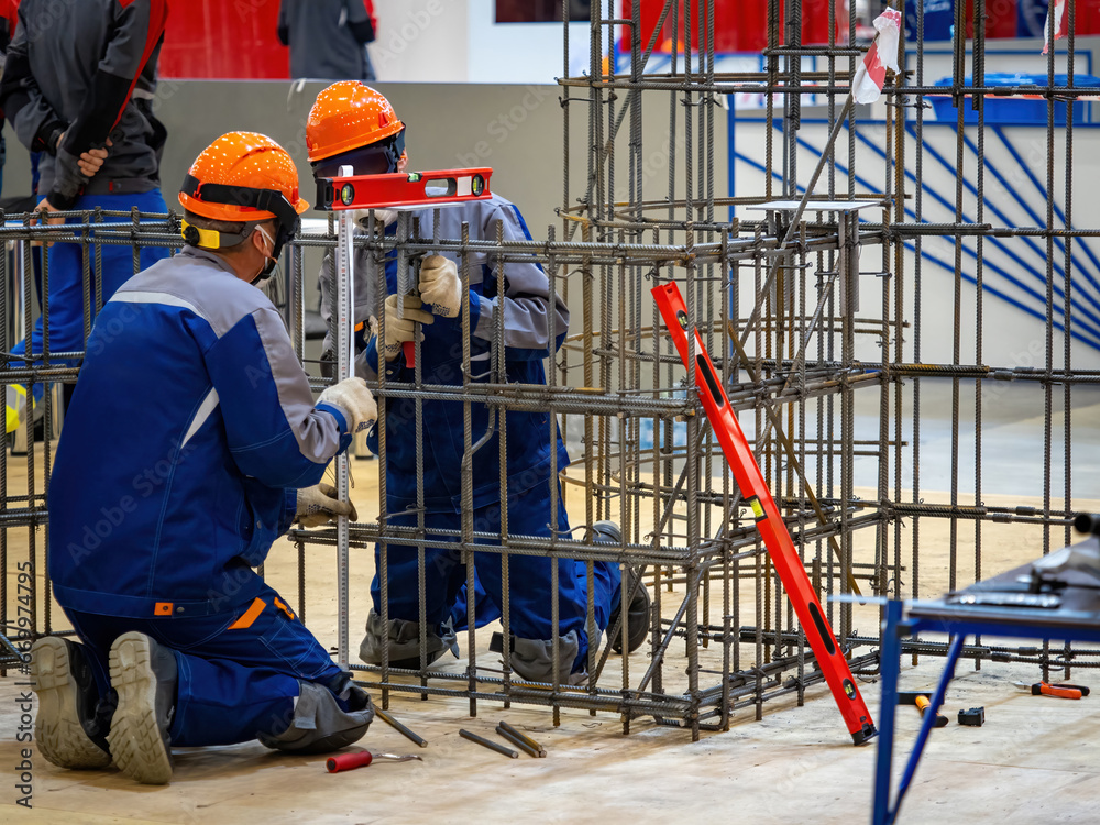 Production reinforcing mesh. Two workers make frame from metal ...