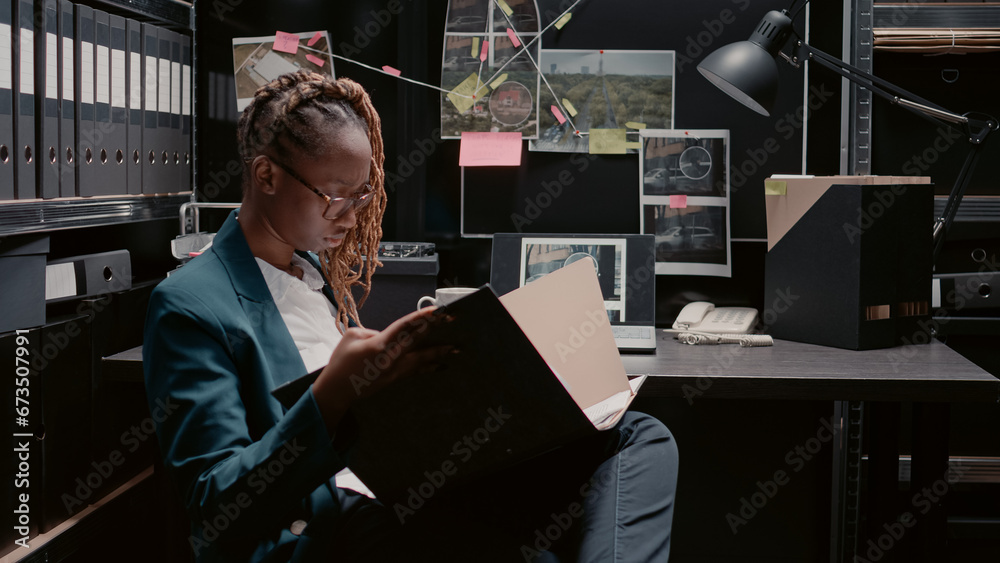 African american policewoman reviewing case files, working on criminal ...
