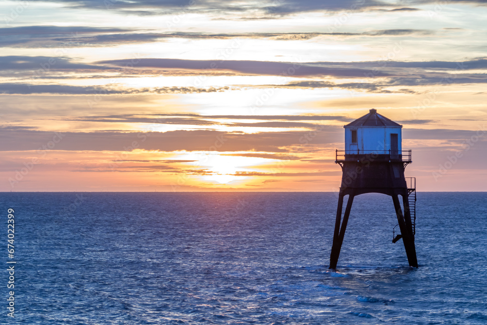 sunrise over a old lighthouse in the sea, Dovercourt low lighthouse, built in 1863 and ...