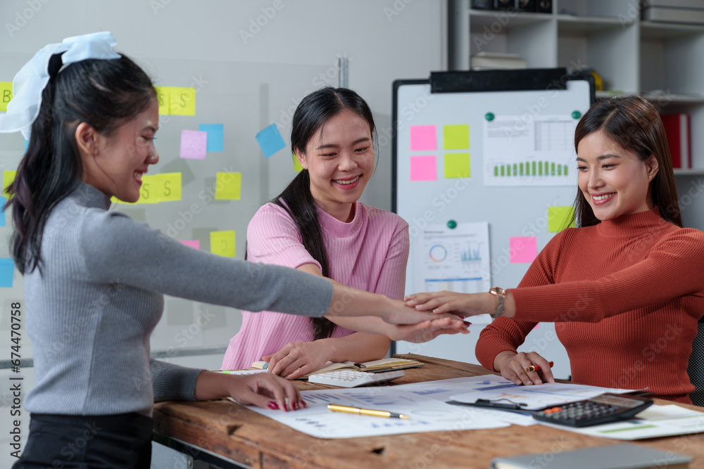 Fotografie Group of young Asian business women holding hands for work ...