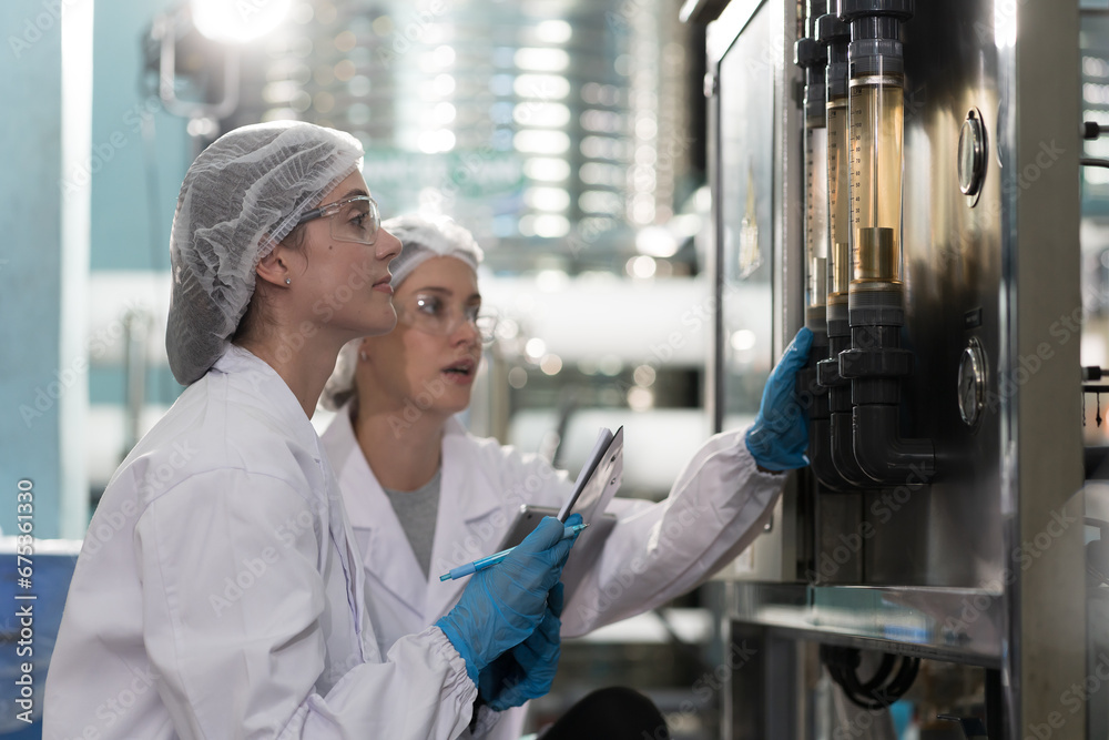 Two female worker wearing uniform, hairnet working and checking of ...