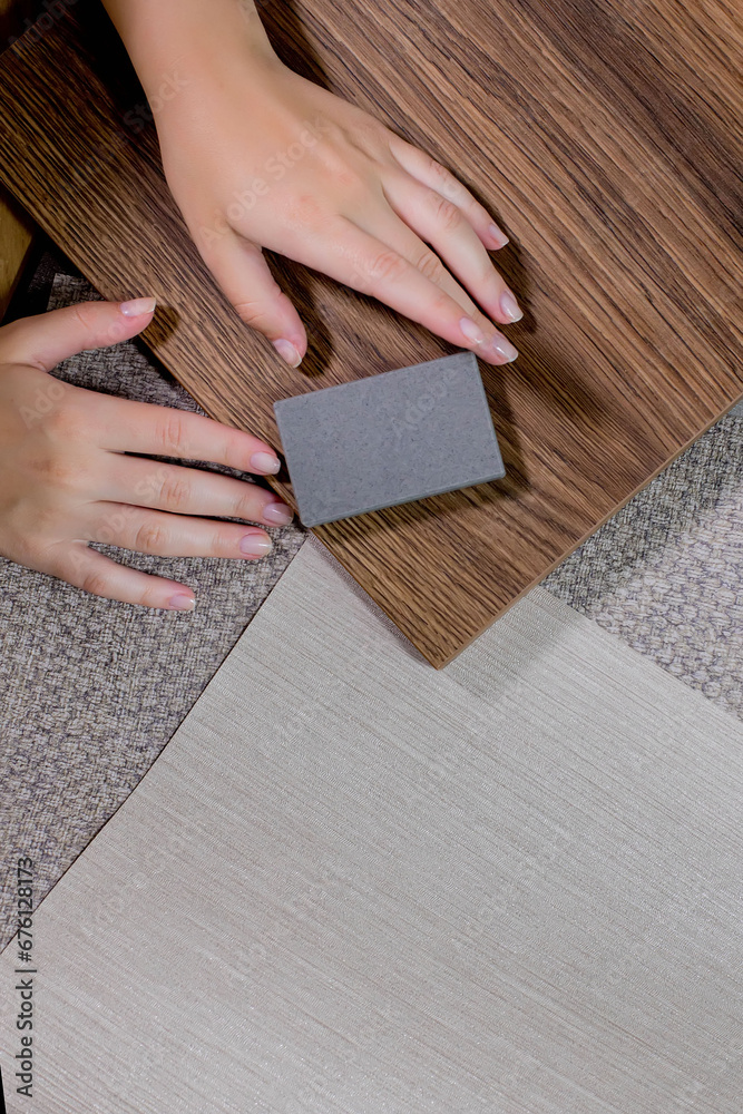 An interior designer's hand selects a palette of sample materials that ...