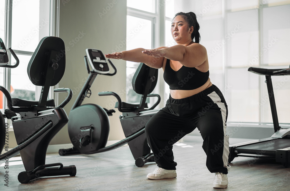Plus size Asian woman exercises in gym. Beautiful overweight woman in ...