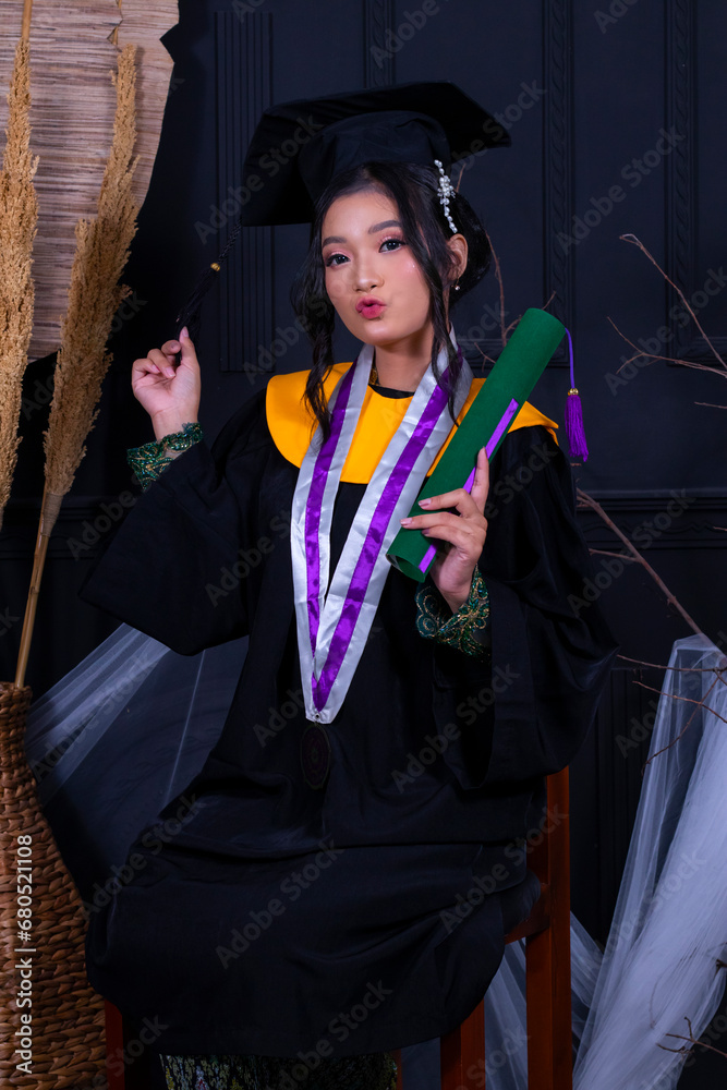 beautiful exotic Asian woman graduating sassy hand holding toga strap ...