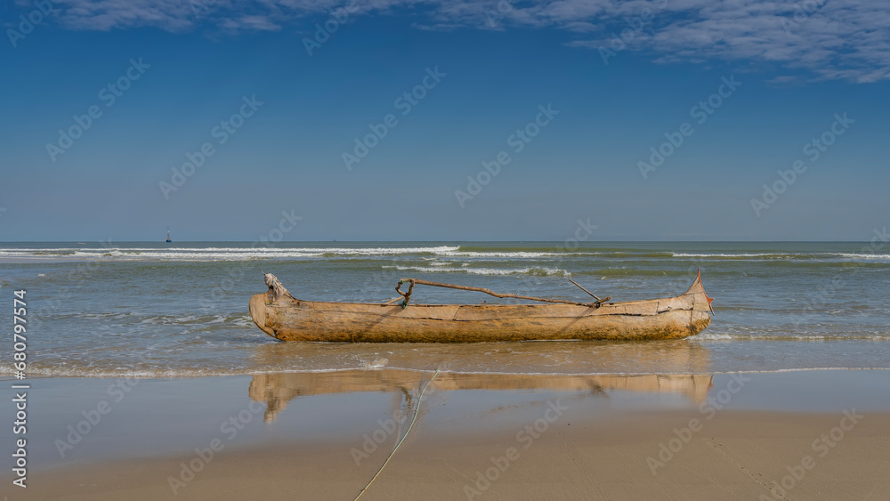 Homemade traditional wooden pirogue in shallow water at low tide. The ...