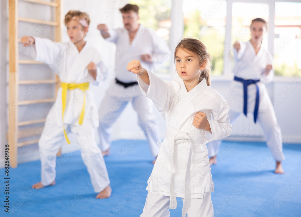 Focused preteen girl with family wearing white kimonos diligently ...