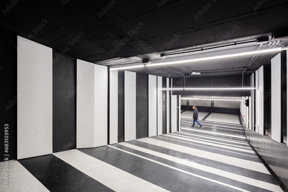 Pedestrian walking through a modern parking garage with striking black ...