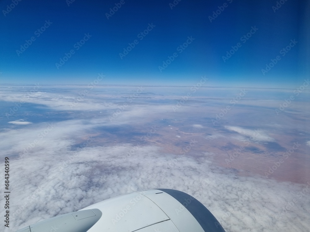 View from an airplane window showing expansive cloudscape, engine, and ...
