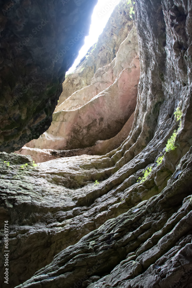 Beautiful curves of rocks in the cave. A ray of sunlight enters the ...