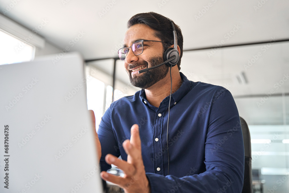Happy Indian call center agent wearing headset talking to client ...