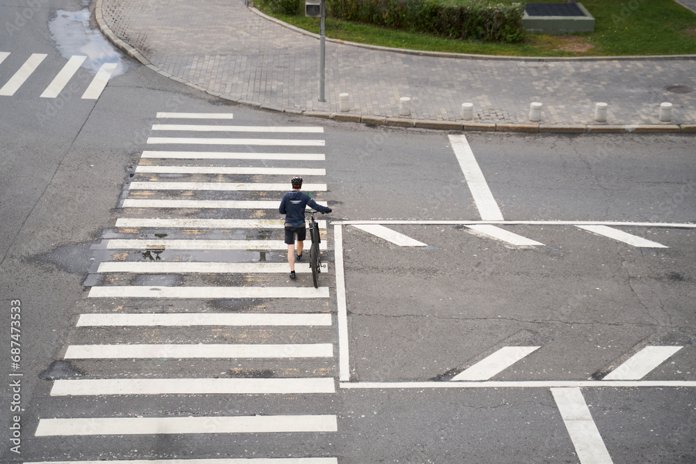 Man crosses the road at a pedestrian crossing and carries a bicycle ...