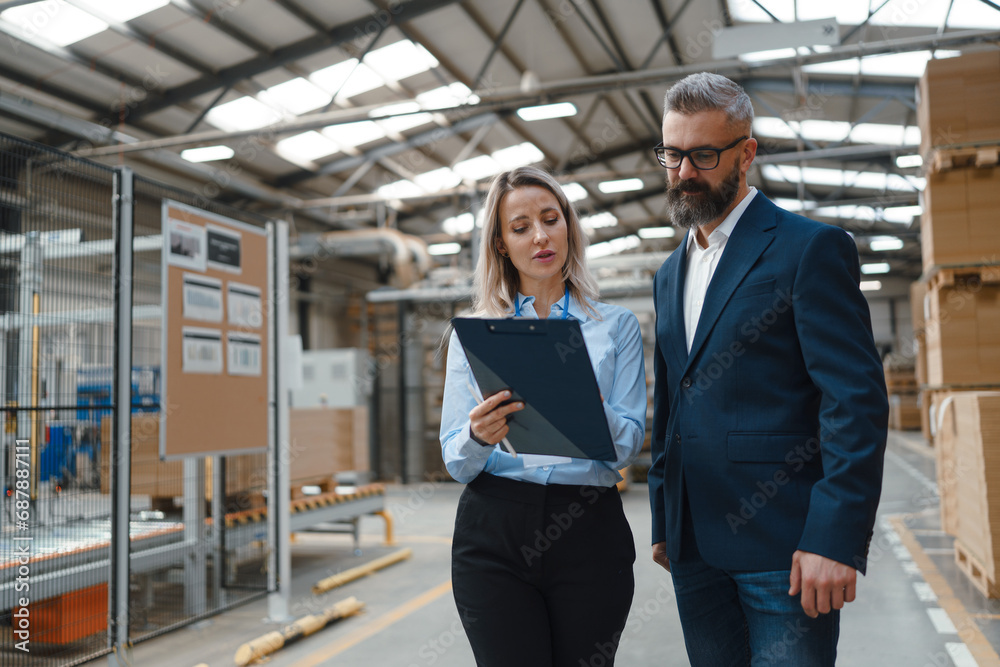 Female warehouse manager talking with logistics employee in warehouse ...