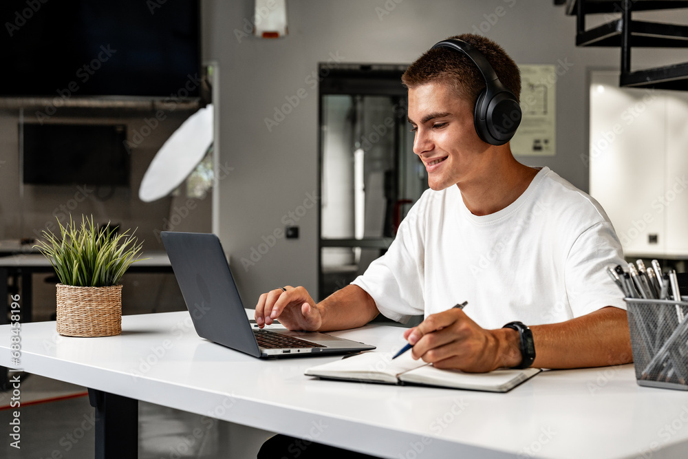 Young man wearing headphones while studying with laptop Stock Photo ...