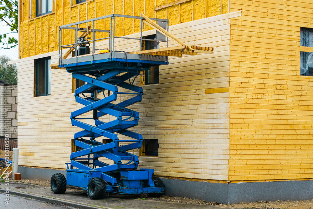 Using a scissor lift in facade cladding works after spraying the facade ...