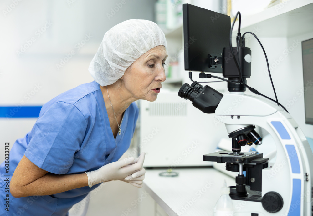 Focused experienced female veterinarian using modern digital microscope ...