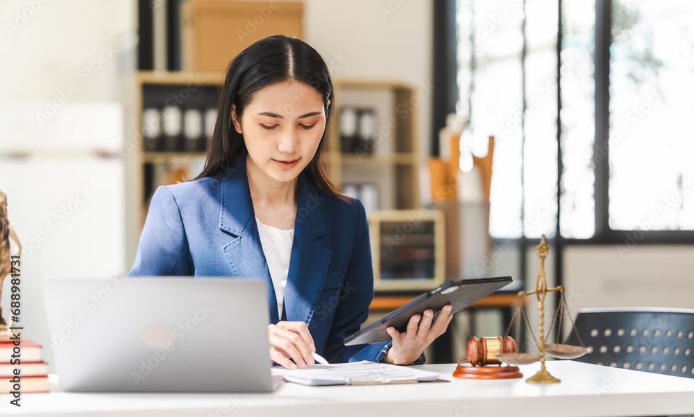 Young attractive Asian female lawyer in formal suit works on tablet ...