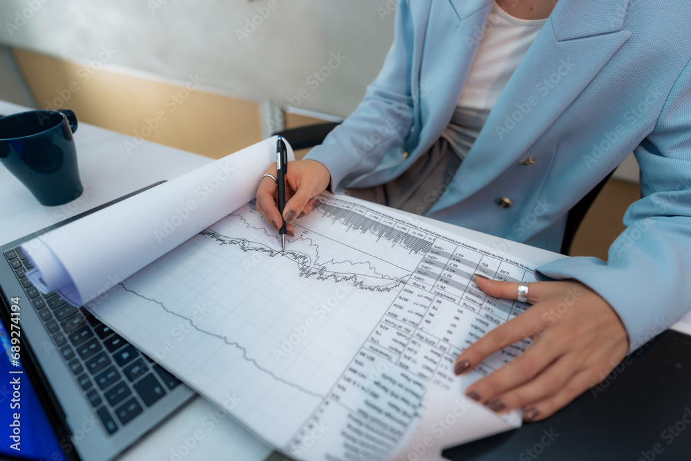 In a close-up shot, hands carefully scrutinize business statistics on a ...