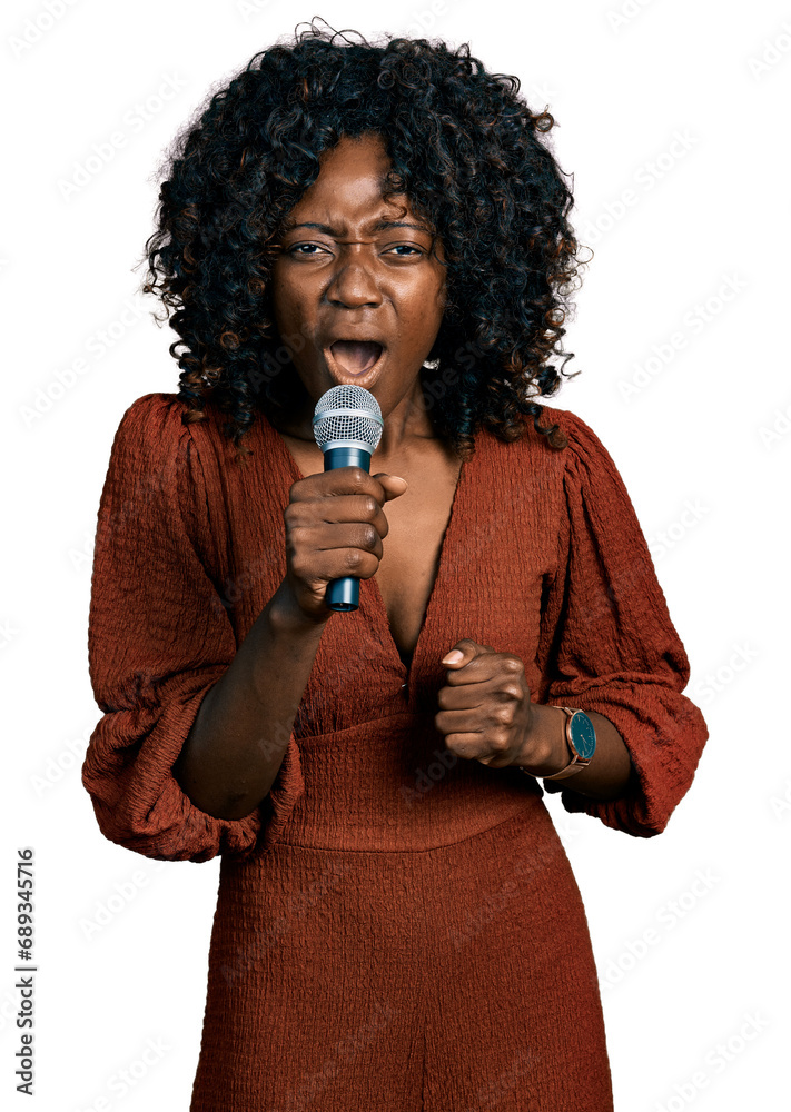 African woman with curly hair singing song using microphone angry and ...