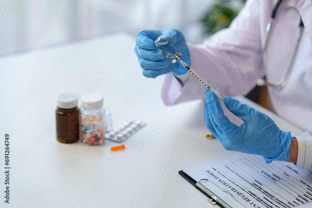 Young doctor holds a syringe and a vial with a vaccine for the ...