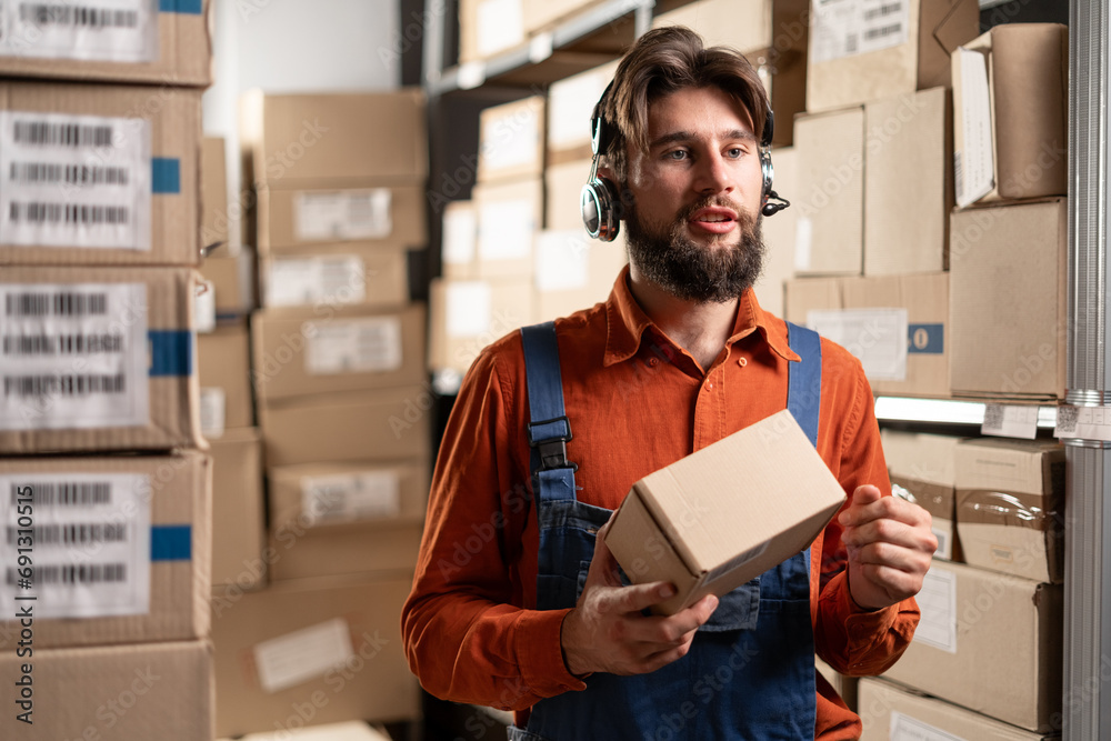 Caucasian male warehouse operator delivering goods dressed in blue ...