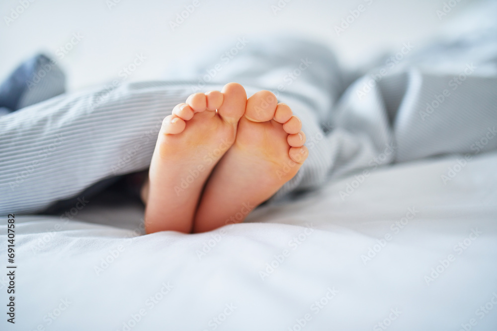 Little child's feet in bed covered with blanket Stock Photo | Adobe Stock