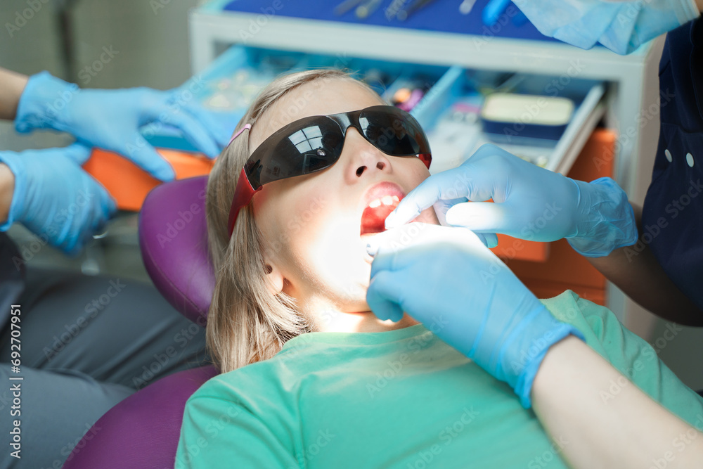 Little scared girl sitting in chair in dentist doctor office ...