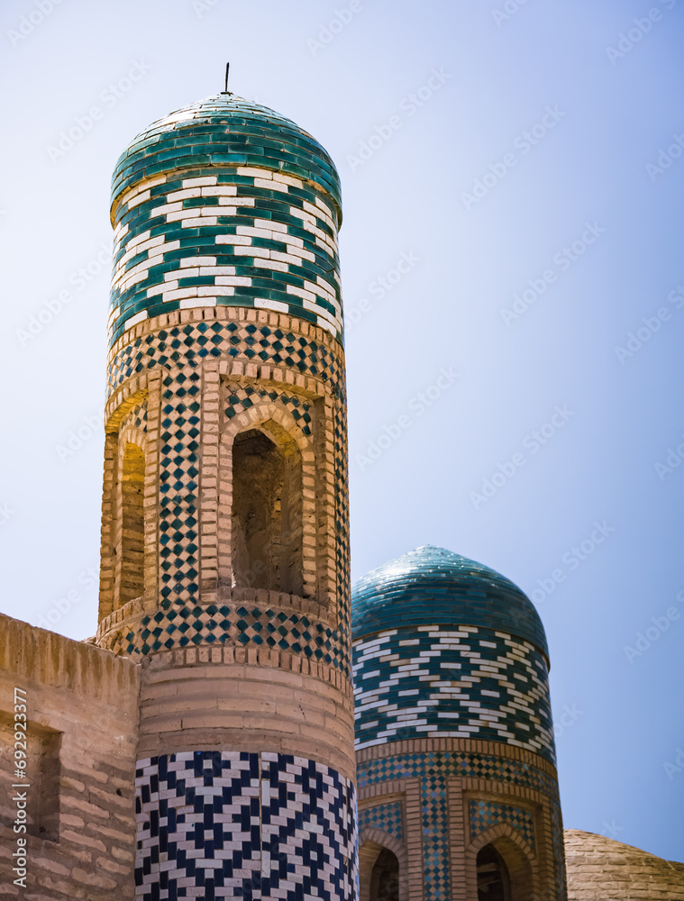 An ancient minaret of a brick mosque faced with ceramic tiles and ...