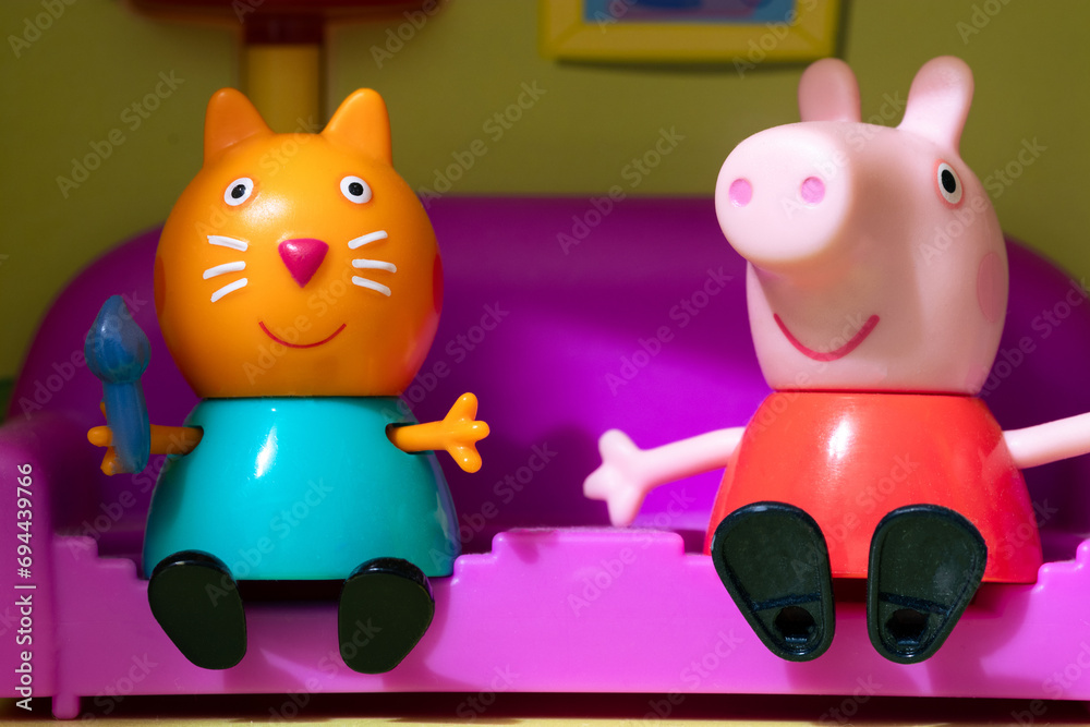 Candy the cat and Peppa the Pig are sittng on the sofa. Peppa Pig's toy ...