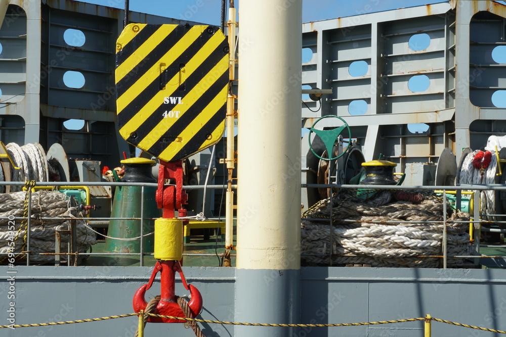 Steel red hook and black and yellow hoist block of ship's cargo crane ...