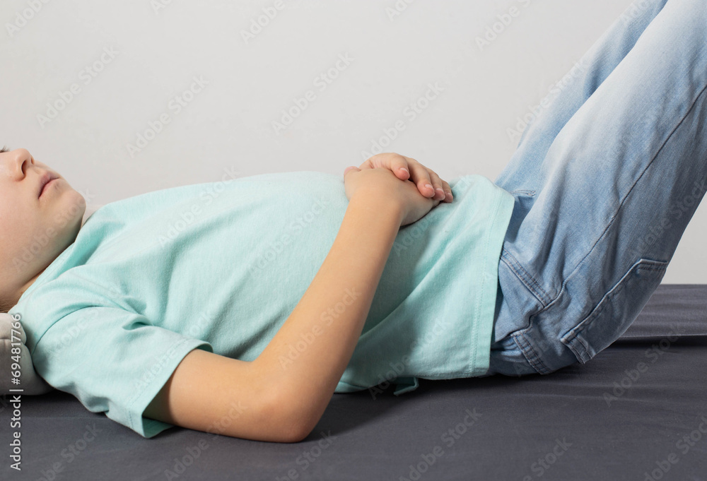 A seven-year-old girl lies and holds her lower abdomen with pain and ...