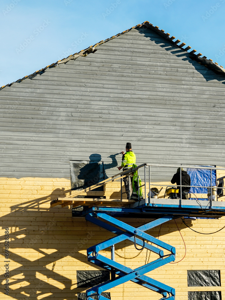 Residential house facade painting works after cladding with wooden ...