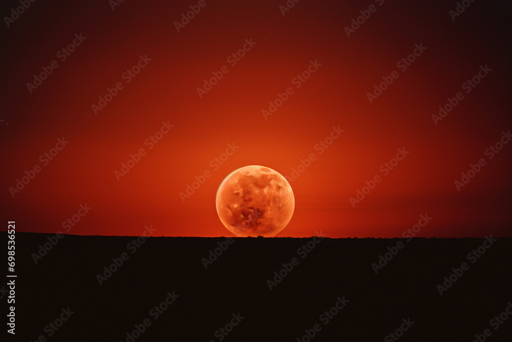 Photograph of a lunar eclipse, showcasing the moon bathed in a reddish glow as Earth's shadow ...