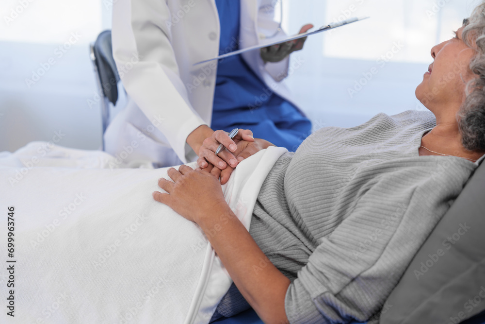 Elderly Asian woman lying in hospital bed looking unwell, with young ...