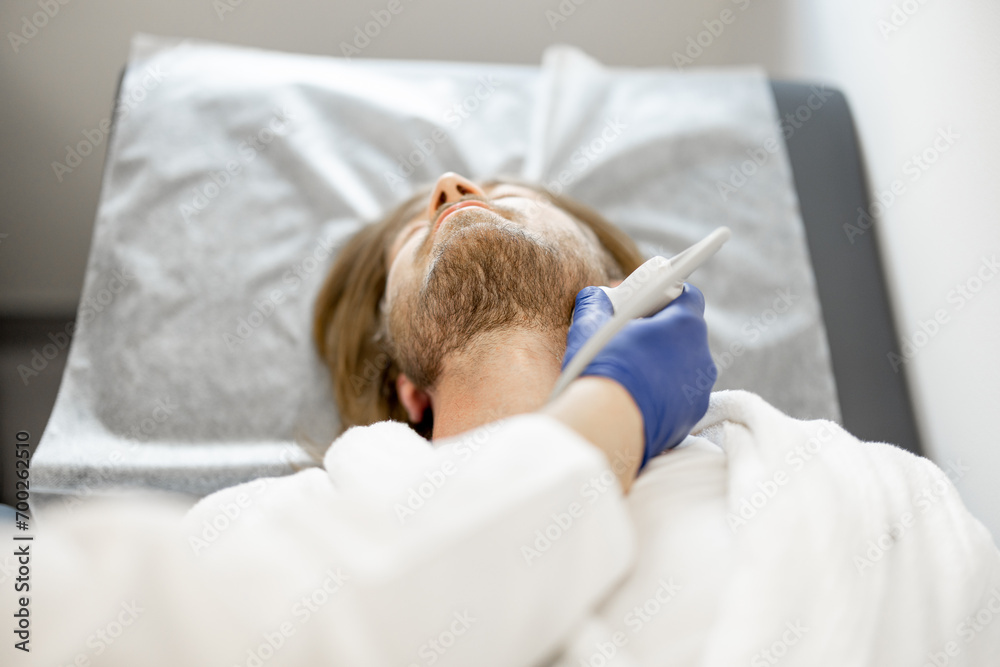 Young guy during an ultrasound diagnosis of the carotid artery. Concept ...