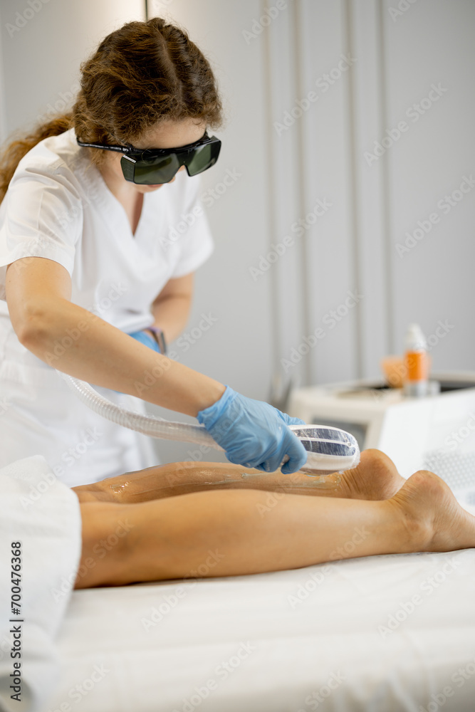 Young worker of a beauty salon during hair removal procedure on a woman ...