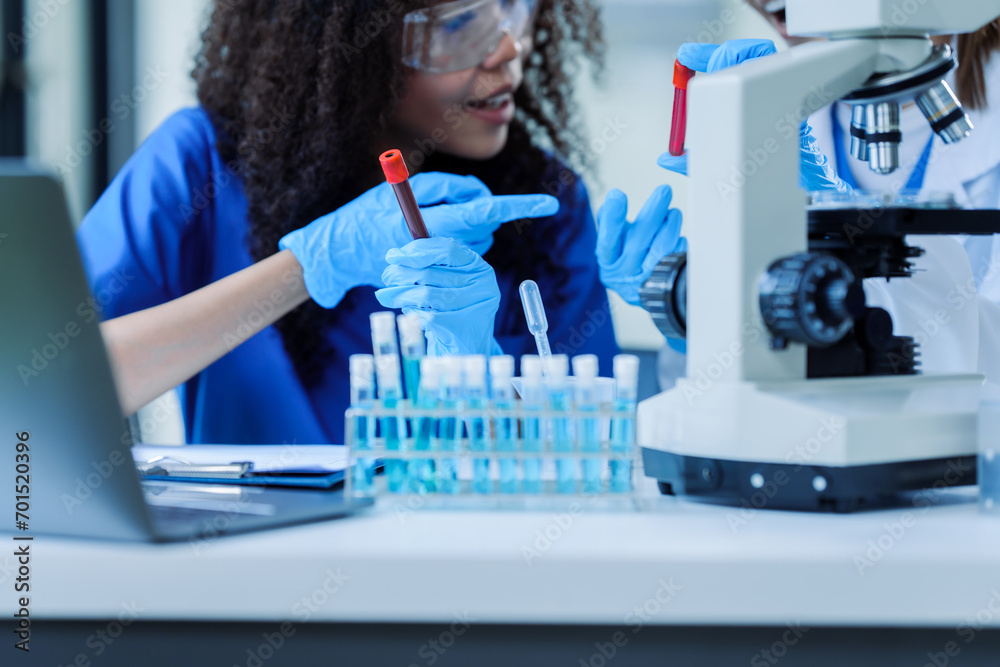 African American and a Caucasian researcher conducting a blood lab test ...